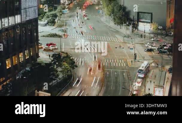 A bustling urban intersection at night captures the continuous flow of ...