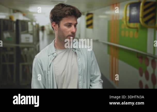 Man with eyes wide and mouth slightly open in a building corridor ...