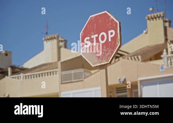 Stop sign against clear blue sky with sun-kissed beige buildings in the ...
