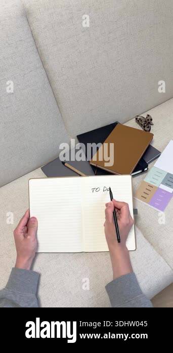 Woman writing her list of plans in notepad on the sofa at home top view ...