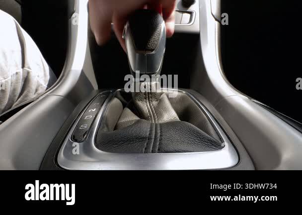 A detailed view of a car gear shift located in the center console. The ...