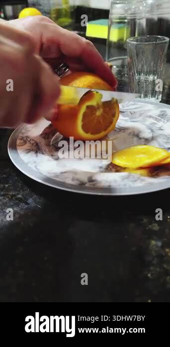Close-up video of a person slicing an orange slice with a knife on a ...