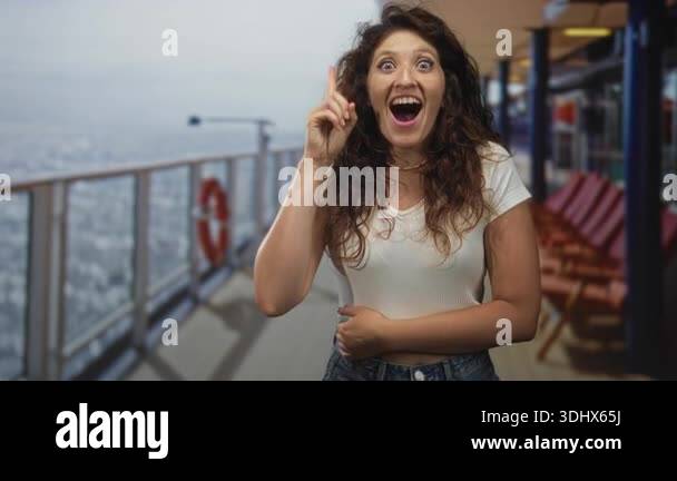 Woman points finger up on cruise ship deck building, smiling with ...