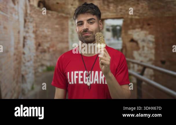 Man in red lifeguard shirt holds icecream covered in nuts at roman ...