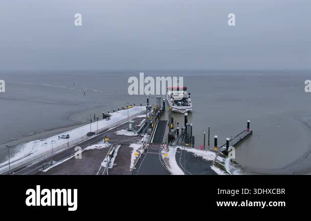 Aerial view of a car ferry arriving at a snowy pier on a cold, overcast ...