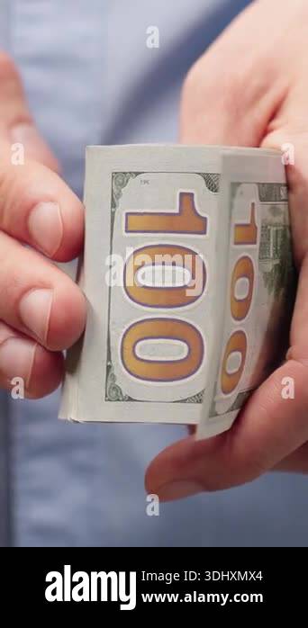 Vertical close-up of male hands counting a pile of 100 dollar bills ...