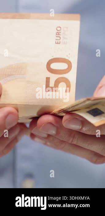 Vertical close-up of male hands counting euro banknotes. Man in blue ...