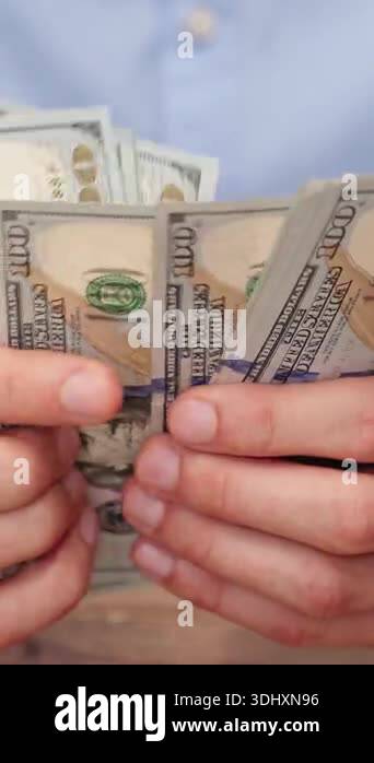 VERTICAL VIDEO: Man counting 100 US dollar bills in close-up ...