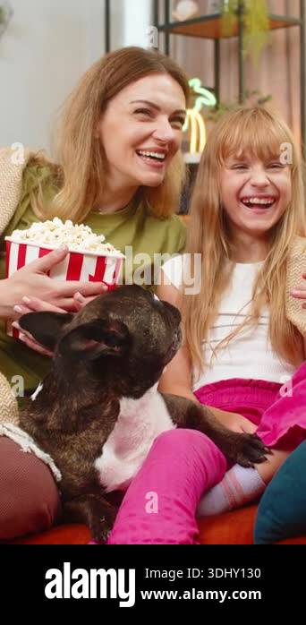 Mother and daughter with French bulldog at home watch comedy share ...