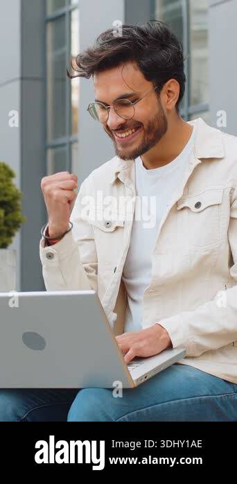 Overjoyed happy young Indian man working on laptop scream in delight ...