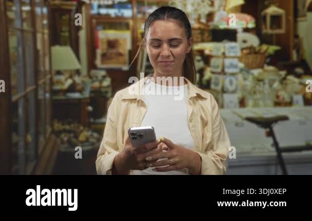 Woman holding smartphone and making ok sign with fingers in a boutique ...