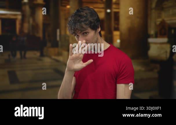 Man in red shirt shielding palm against bright light under church ...