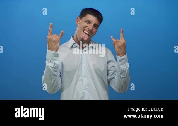 Young hispanic man sticks out tongue and shows rock horns with both ...