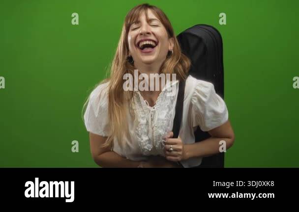 Young caucasian woman carrying a black guitar case laughing with eyes ...