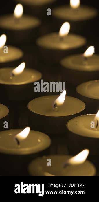 Group of burning small candles at a memorial. Many glowing tea lights ...