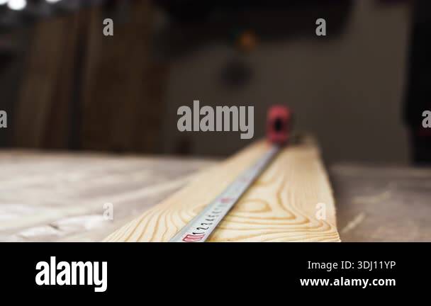 Close up of carpenter hand in blue glove measuring wooden plank with ...