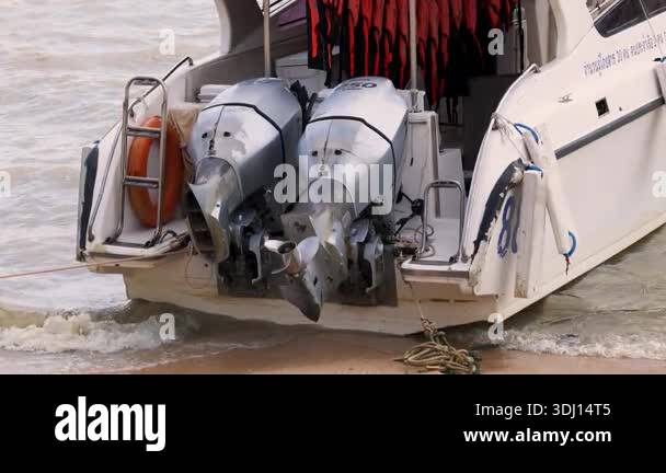 Boat stranded on beach with damaged outboard engine propeller visible ...