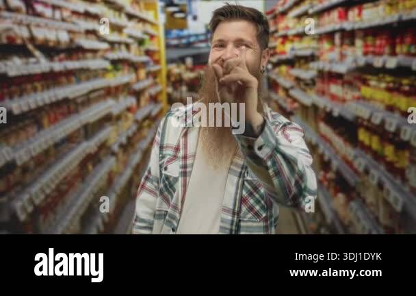Man with beard smiling places thumb and pinky hand to ear as phonecall ...