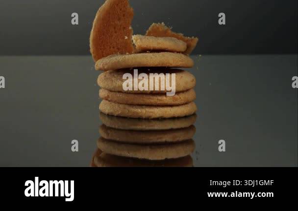 A stack of five golden sugar cookies on a reflective table with another ...