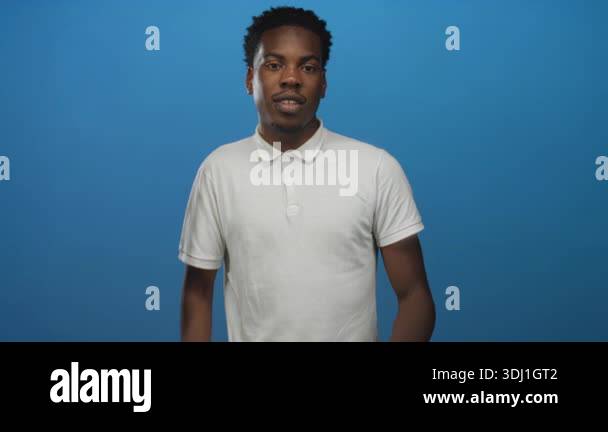 Man with raised hand making peace sign against a bright blue studio ...
