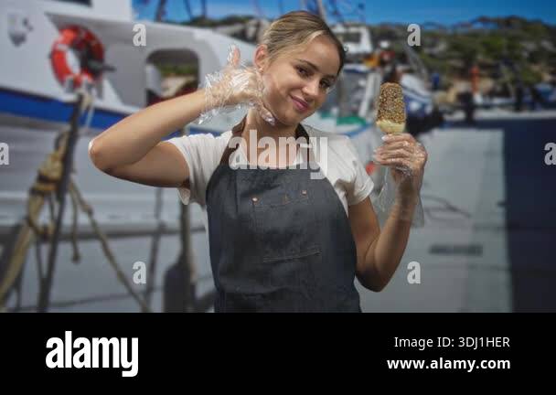 Woman holding ice cream bar and making phone hand gesture at port pier ...