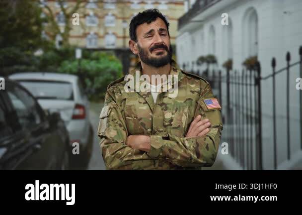 Man with beard wearing military uniform stands outdoors in city street ...