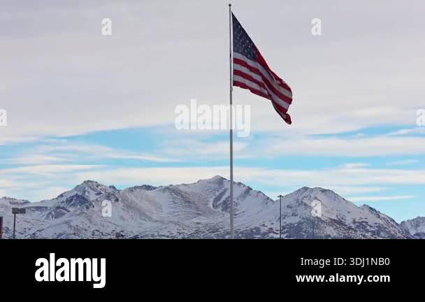 American flag proudly waving against the backdrop of snow-covered ...