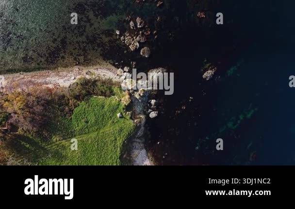 Aerial view shows a rocky coastline where the green land meets deep ...