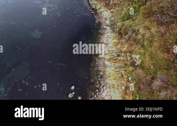 Calm waters meet a rugged shoreline in this aerial view. The rocky ...