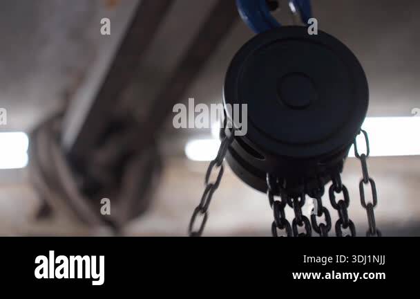 Close-up of a black chain hoist pulley system slowly moving in an ...