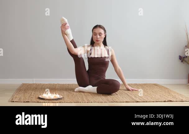 Young woman practicing advanced yoga stretch indoors. Seated pose with ...