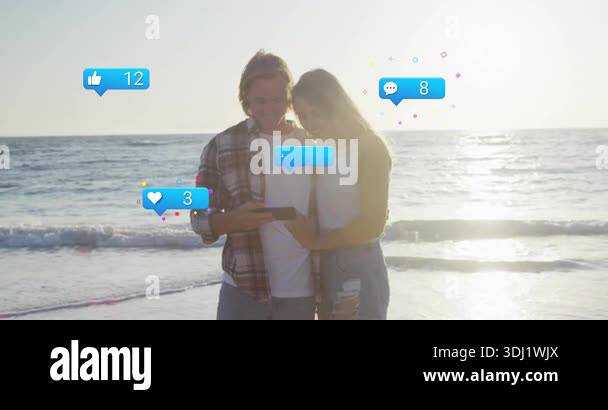 Couple tapping smartphone on sandy beach at sunset scrolling generating ...