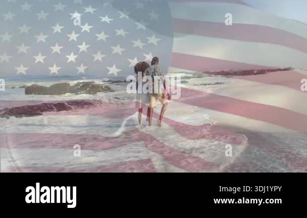 Man embracing woman guiding stepping into surf under flag overlay ...