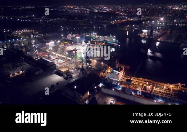 Night aerial video of a ship repair yard with dry docks, cranes and ...