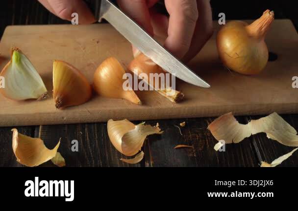 Close-up of hands skillfully slicing yellow onions on a wooden cutting ...