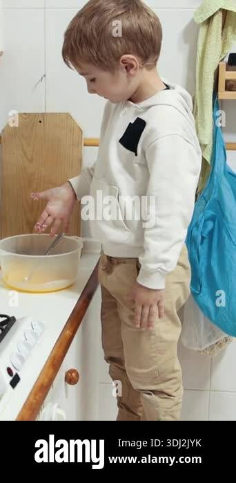 Child learning to cook, adding ingredients and mixing in a bowl on ...