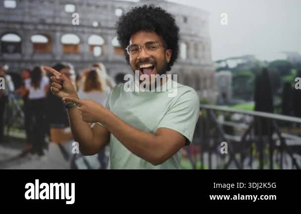 Man with glasses smiling and pointing by the iconic roman coliseum ...