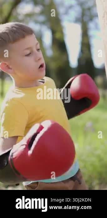 Child boxer training outdoors, hitting a tree with boxing gloves Stock ...