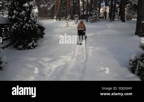 Strong man moves modern snow blower along walkway and snow gathers ...
