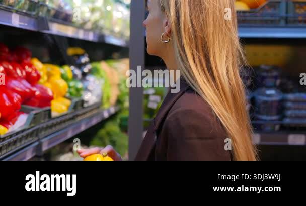 Woman choosing and smells red bell pepper while selecting vegetables in ...
