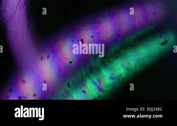 Defocused emulsion spill. Circling fluid. Green purple neon color paint ...