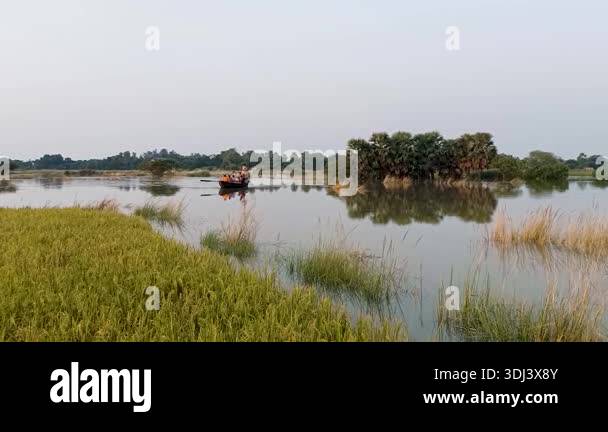 A small traditional boat carrying people glides across a calm river ...