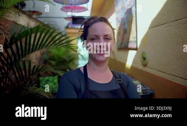 Portrait of restaurant server shows friendly smile and steady gaze ...