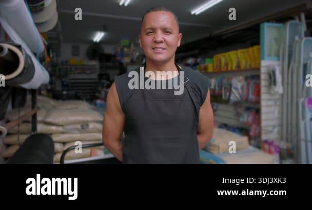 Hispanic hardware store owner facing camera inside workplace ...