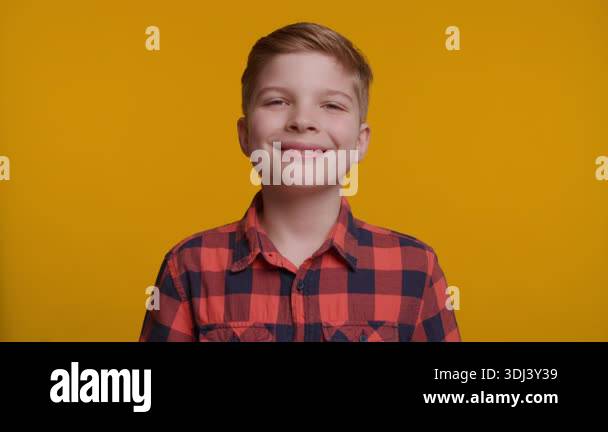 A cheerful boy gives a thumbs-up while looking directly at the camera ...