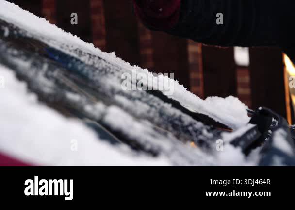 Hand scraping windscreen on a car covered in snow medium zoom shot ...