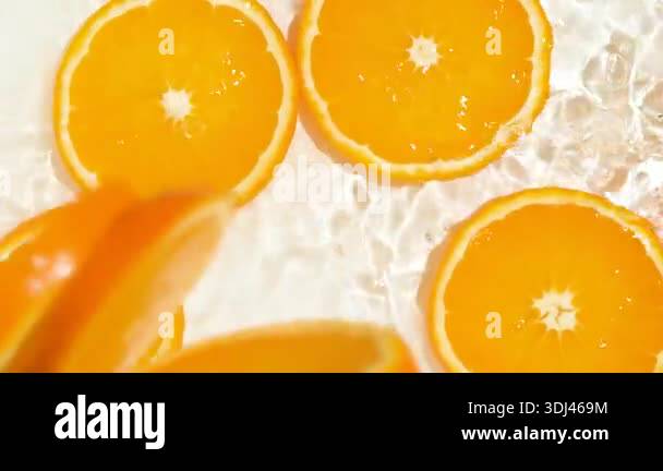 Fresh slices of oranges falling into orange water, splash water, slow ...