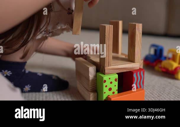 focused caucasian girl balancing tall wooden tower, delicate hand ...