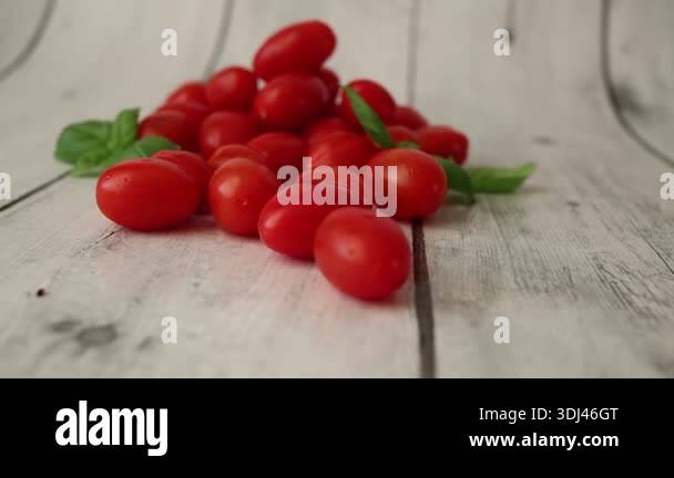 Cherry tomatoes spilling from glass jar on white wooden table.Fresh red ...