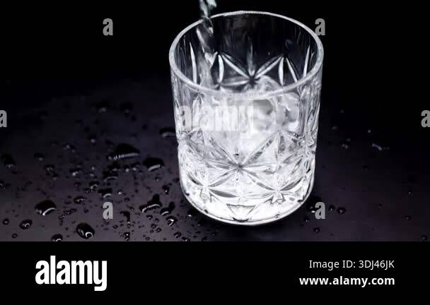 Fresh clean water pouring into a glass on a black background with water ...